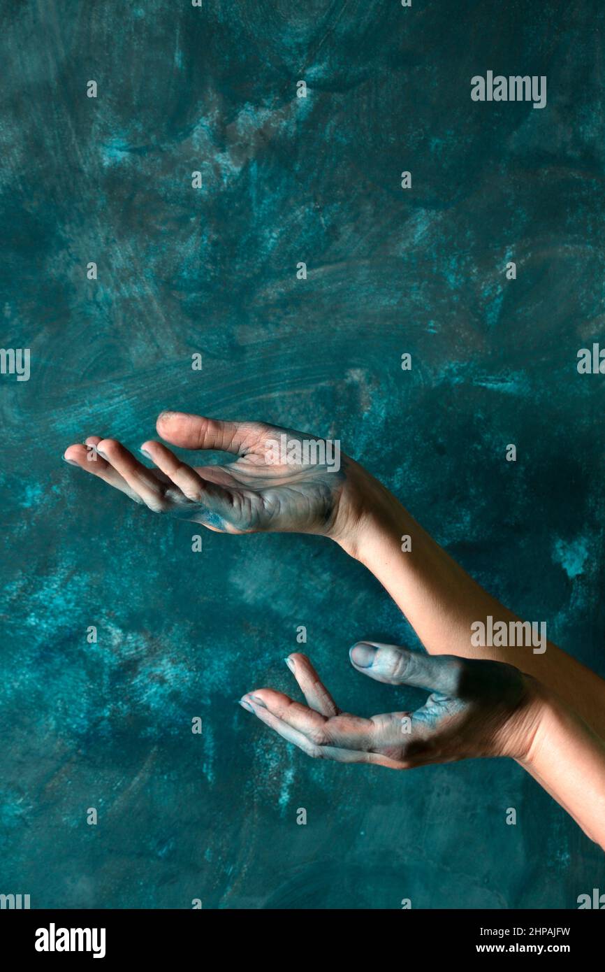 Female hands are stained with blue paint against a blue wall Stock ...