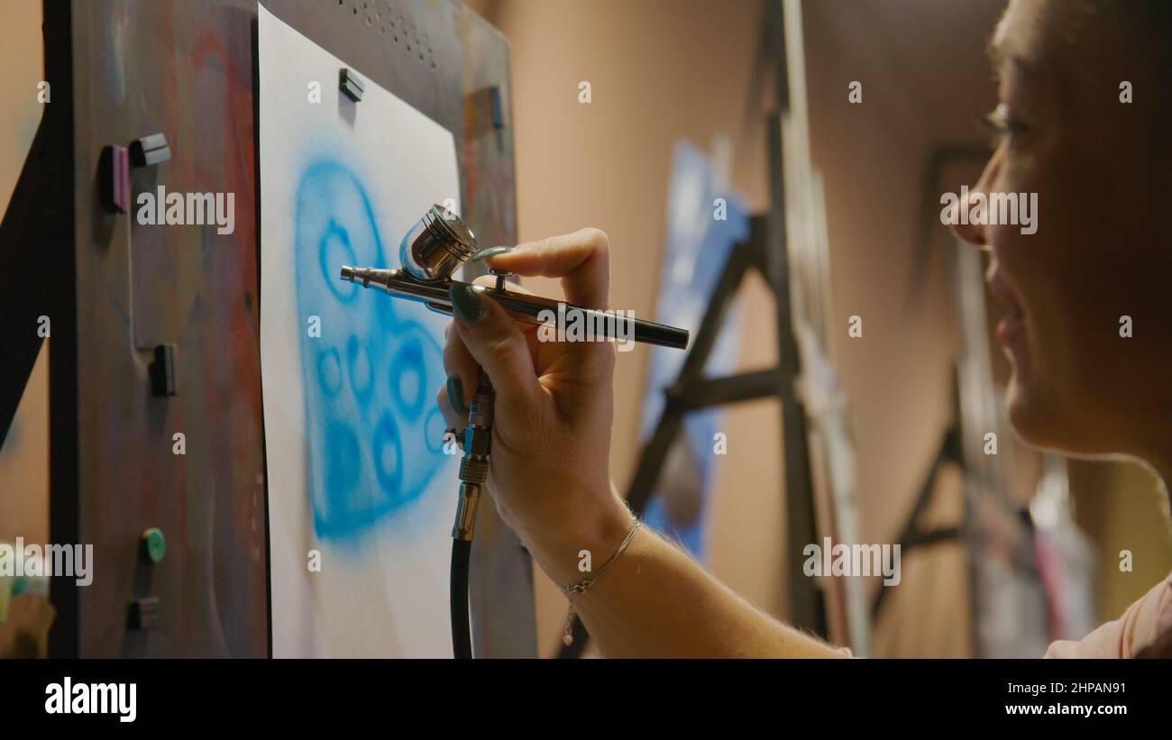 Woman artist learns to paint with airbrush with acrylic dye, paper and ...