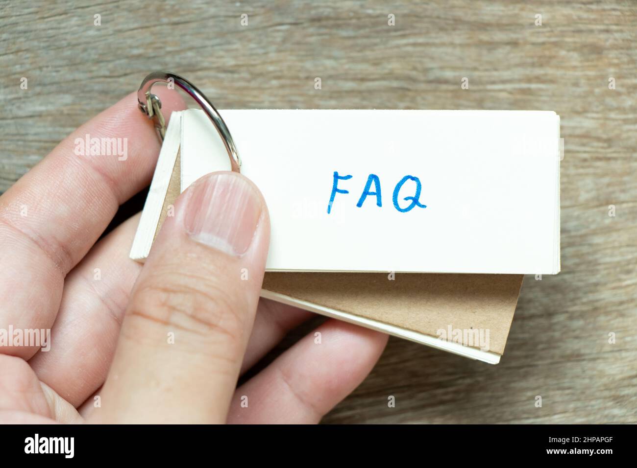 Man hold the flash card with handwriting word FAQ (Abbreviation of ...