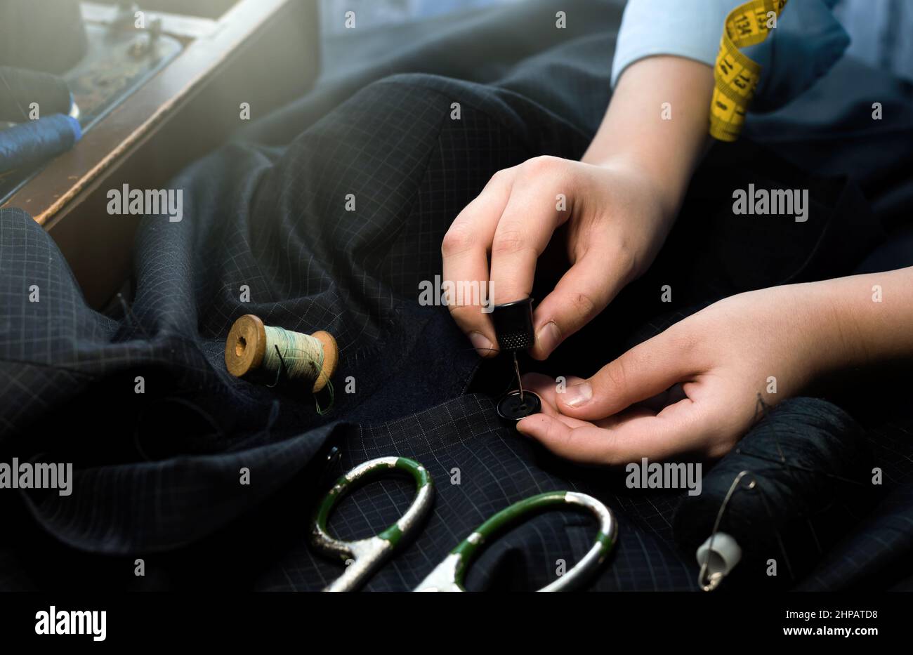 The tailor's hands sew clothes with a needle and thread. Tools for a ...