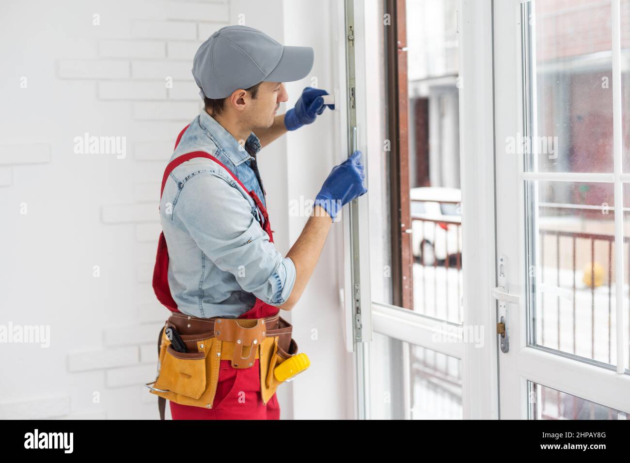 handsome young man installing bay window in a new house construction ...