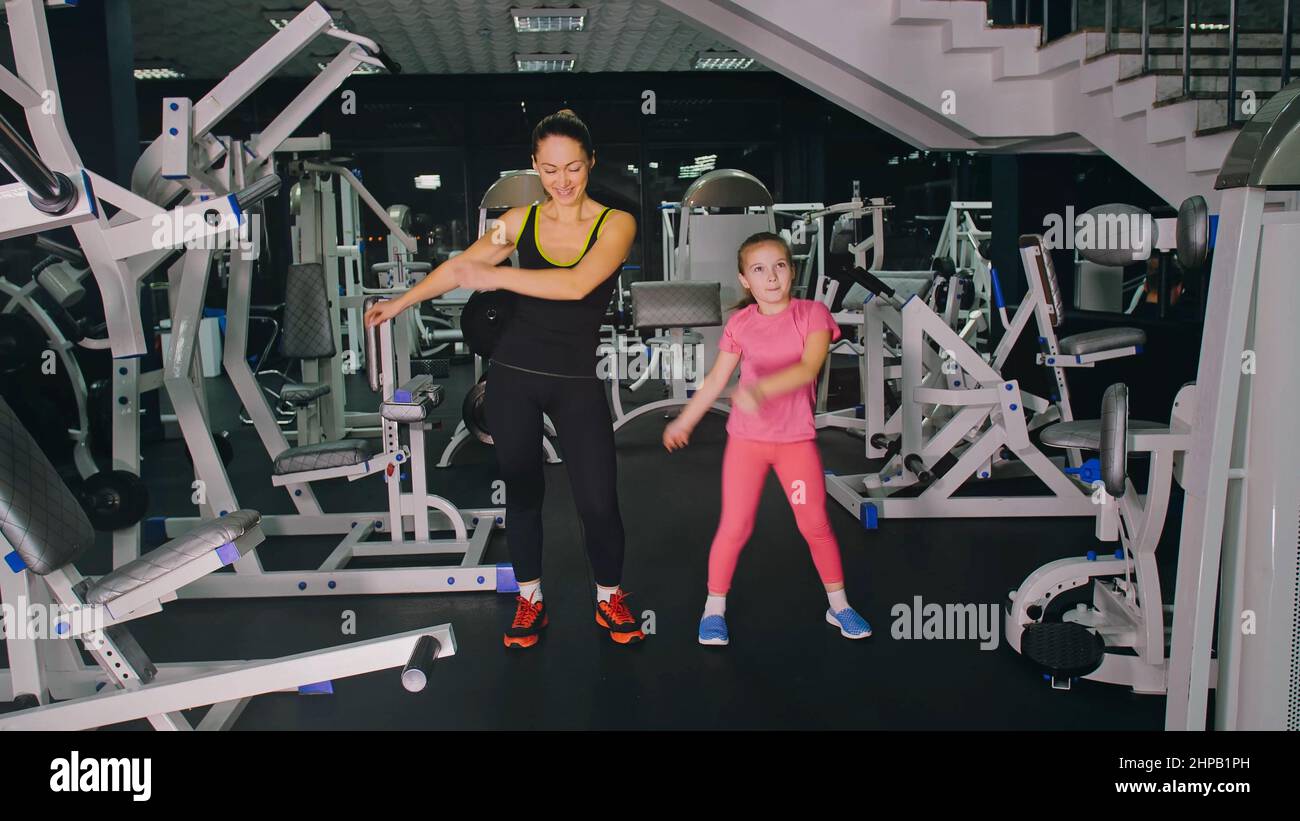 Mother and daughter in the gym, family performs physical doing ...