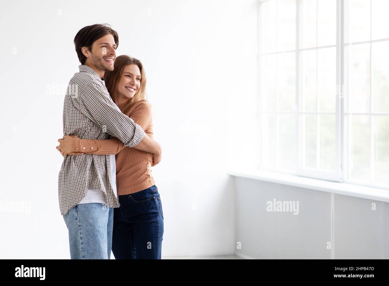 Cheerful millennial caucasian male and female hugging, looking at ...