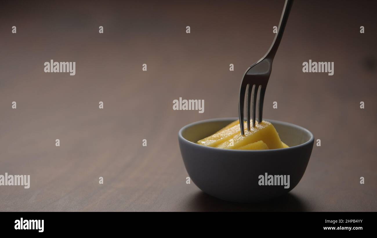picking fresh mango piece from blue bowl with a fork, wide photo Stock ...