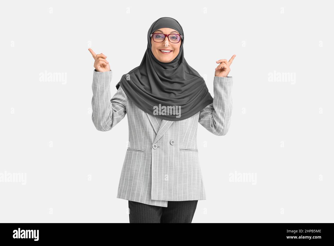 Portrait of Muslim secretary pointing at something on light background ...