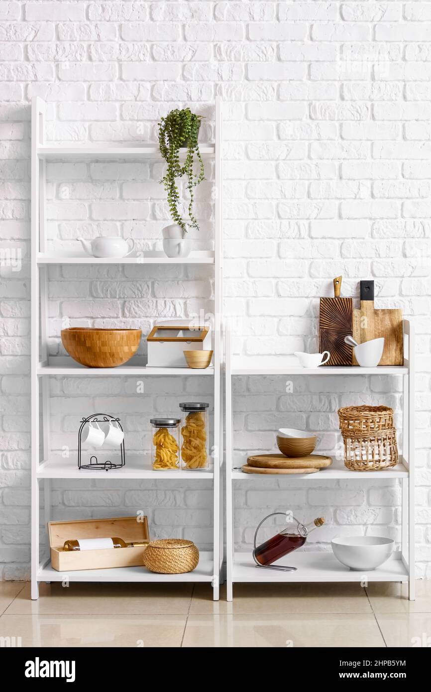 Modern shelf units with kitchenware near white brick wall Stock Photo ...
