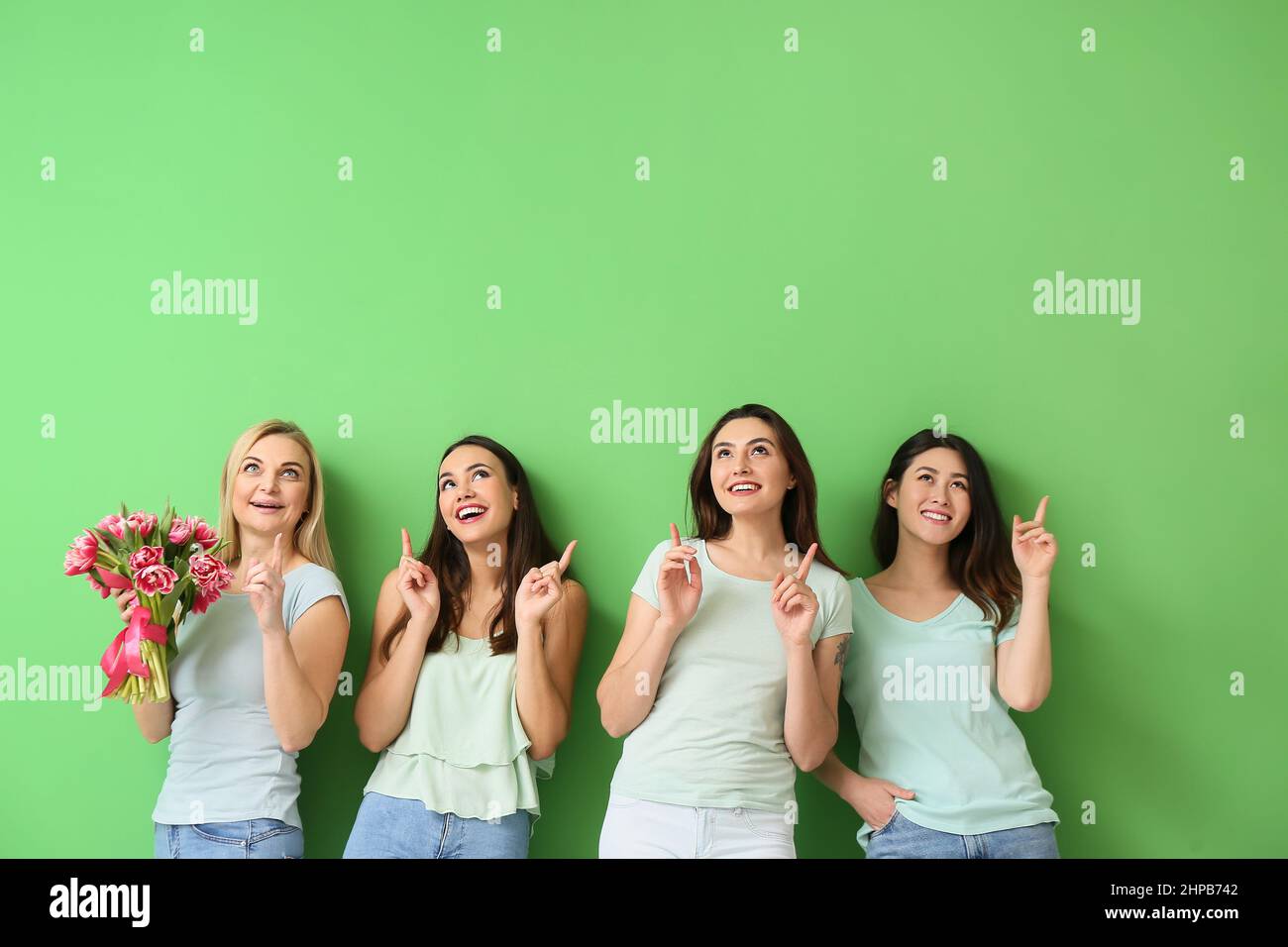 Beautiful women with flowers pointing at something on green background ...