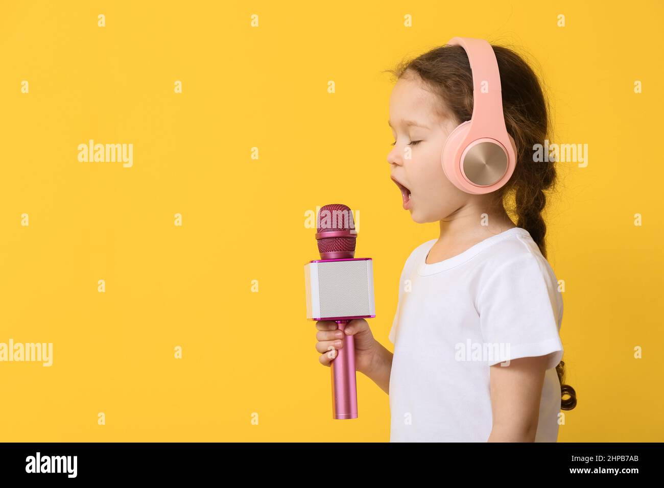 Singing cute little girl with microphone on color background Stock ...