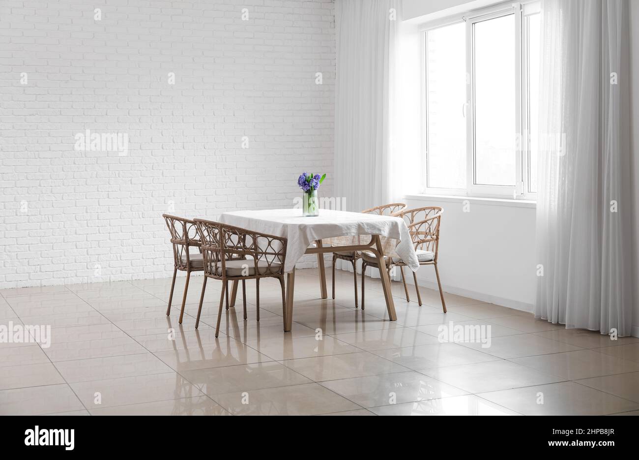 Dining table with flowers and chairs in big light room Stock Photo - Alamy