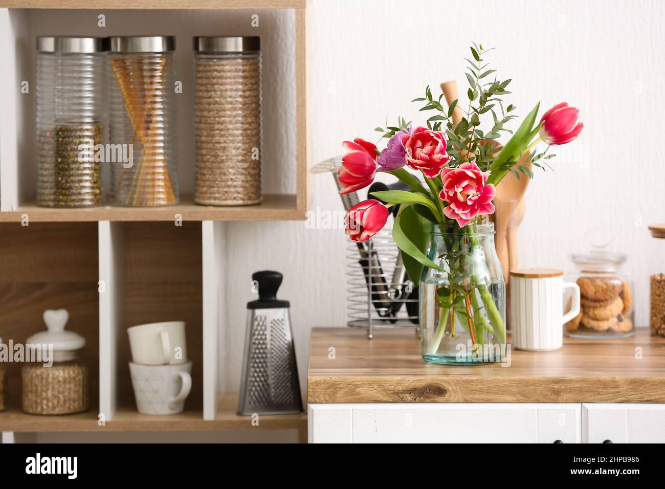 Vase with flowers and different utensils on kitchen counter Stock Photo ...