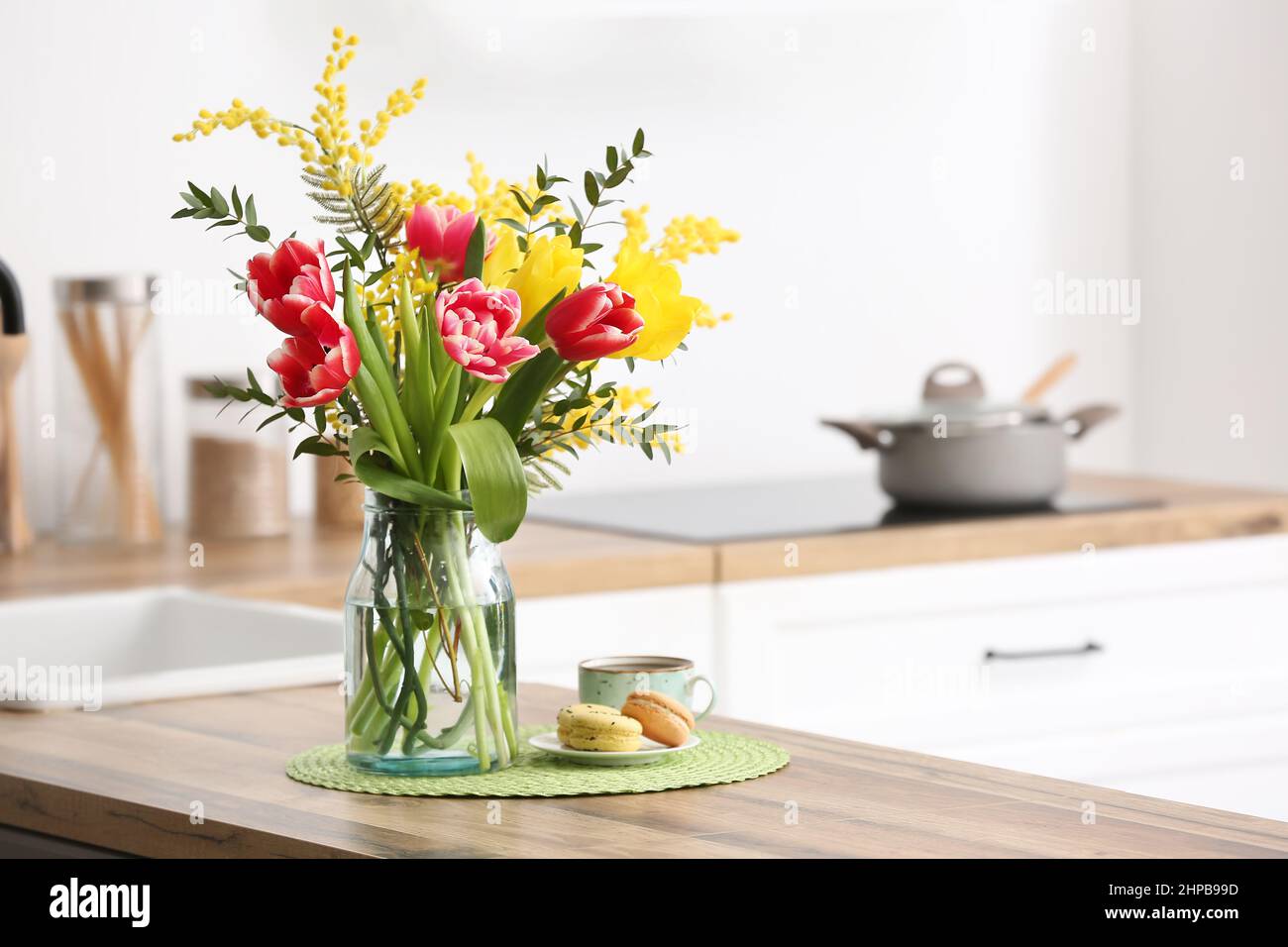 Vase with beautiful flowers, macarons and cup of coffee on kitchen ...