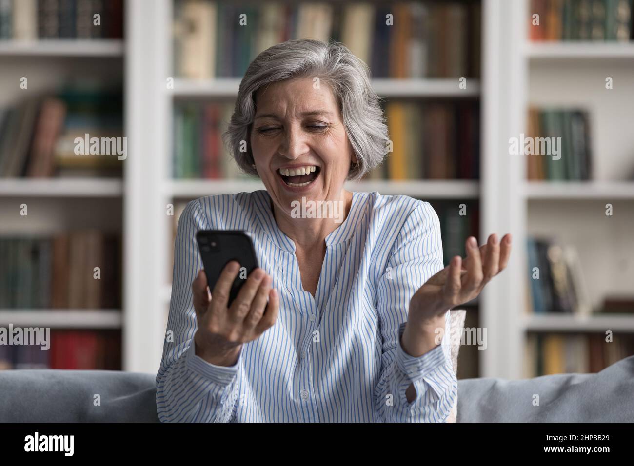 Surprised happy mature woman laughing using cellphone at home Stock Photo - Alamy