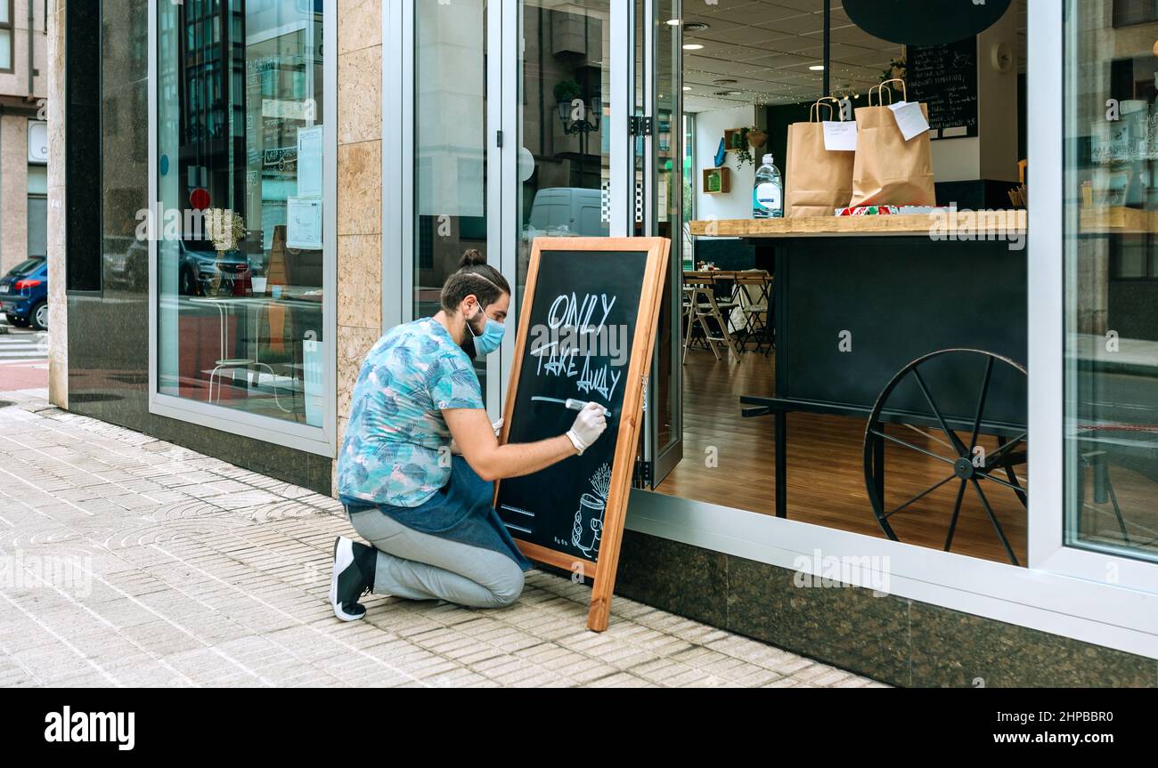 Restaurant owner writing on a blackboard Stock Photo - Alamy