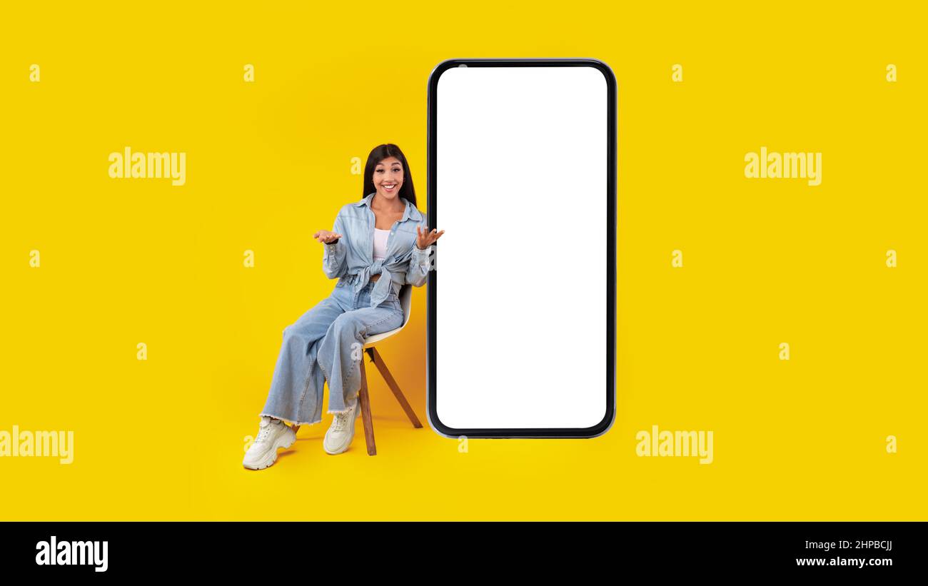 Happy lady presenting big white mobile phone screen Stock Photo - Alamy