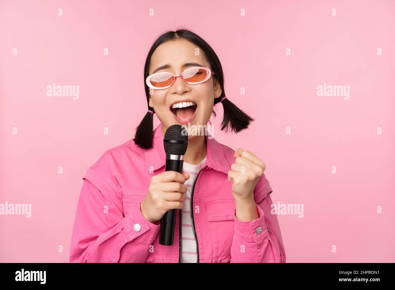 Happy beautiful asian girl singing with mic, using microphone, enjoying ...
