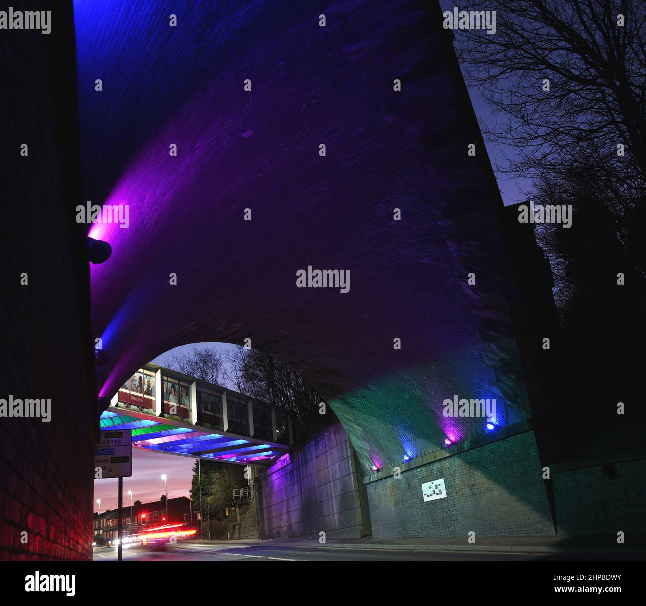 Illuminated Purple Skewed Dark Brick And Metal Railway Bridge Over a ...