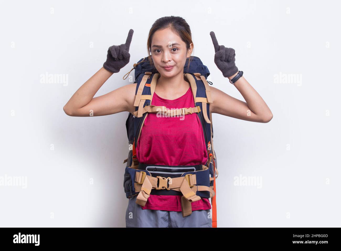 Young asian hiker woman with backpack pointing finger on empty space on ...