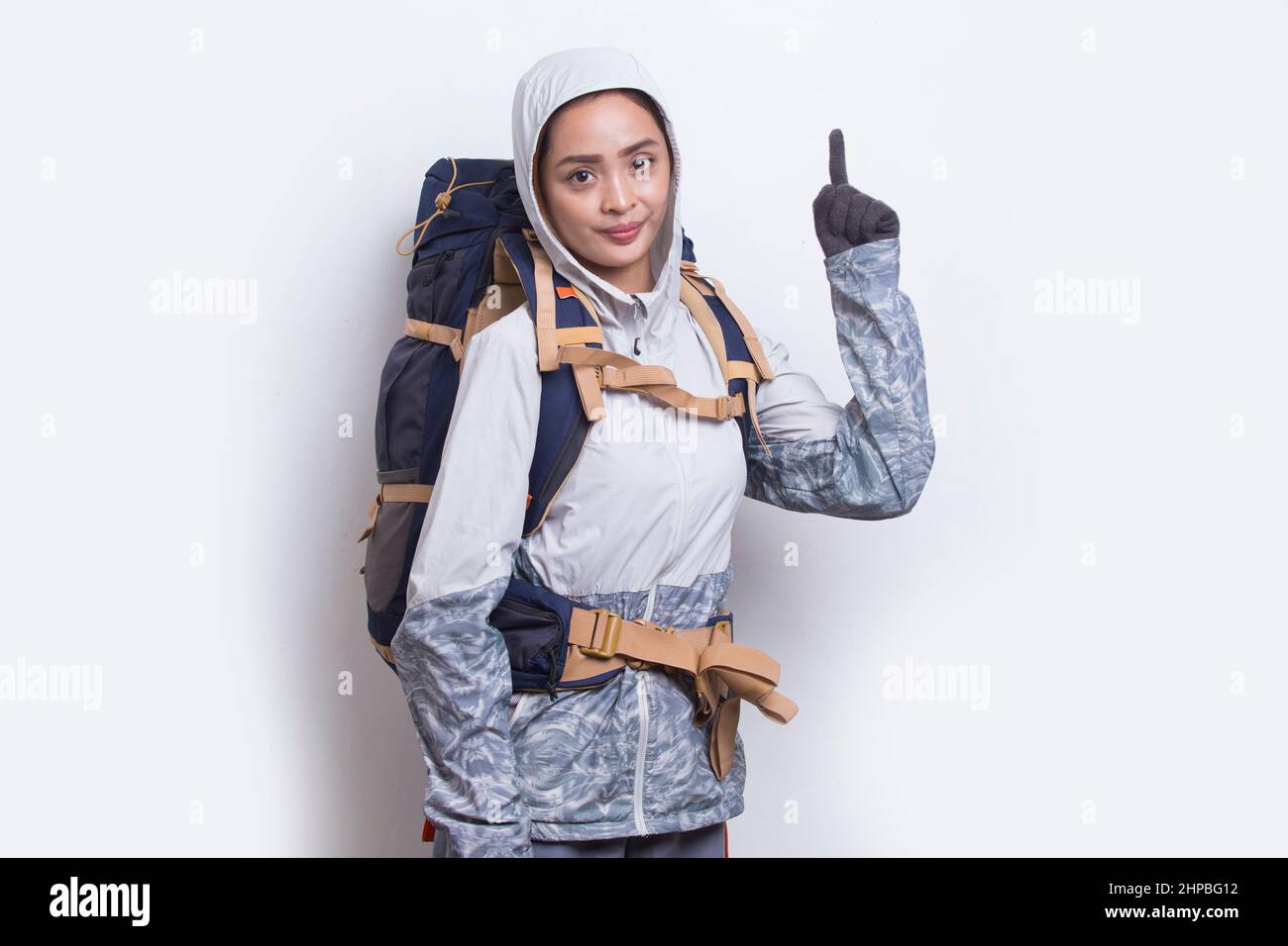 Young asian hiker woman with backpack pointing finger on empty space on ...