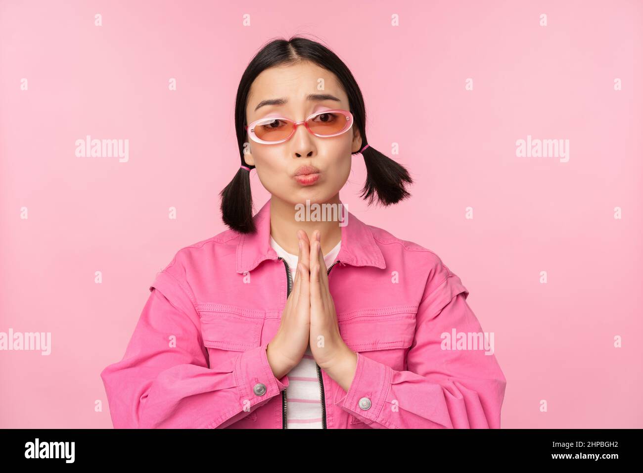 Please. Cute asian girl asking favour, begging, standing against studio ...