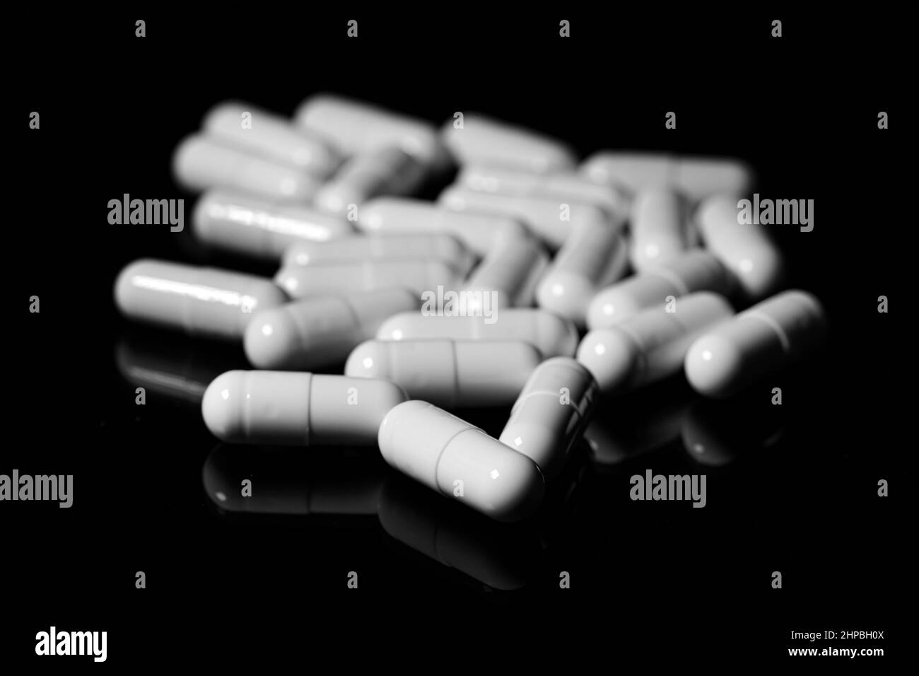 Macro Close up of white painkiller capsule on a reflective black ...