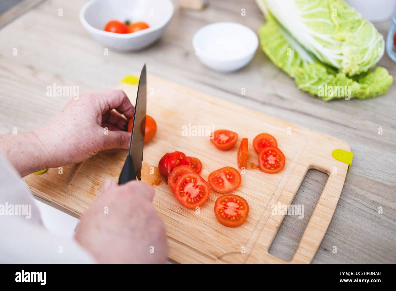 Adult woman hands cooking cutting tomatoes at the kitchen in kitchen ...