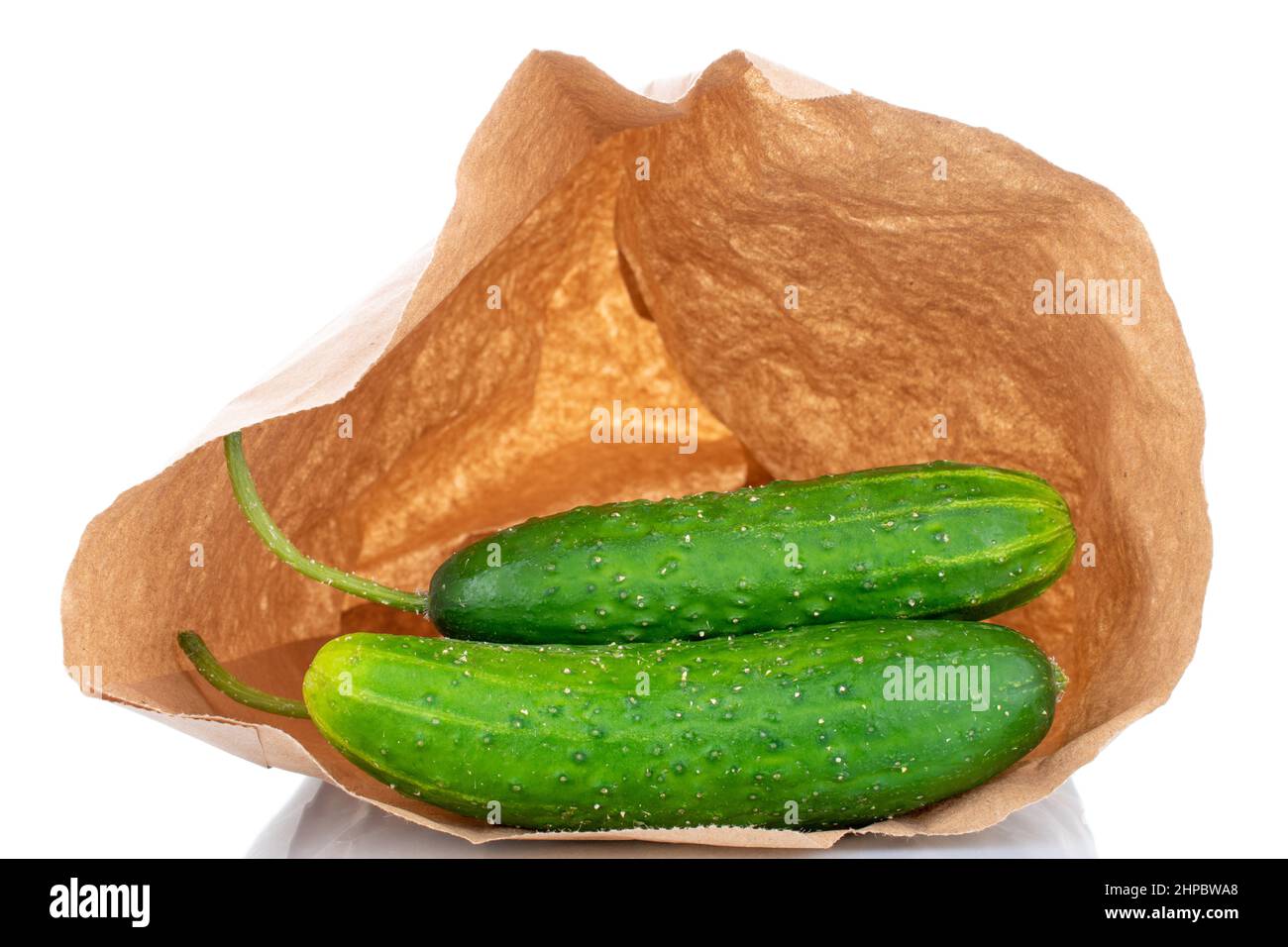 Two ripe green cucumbers in a paper bag, macro, isolated on a white ...