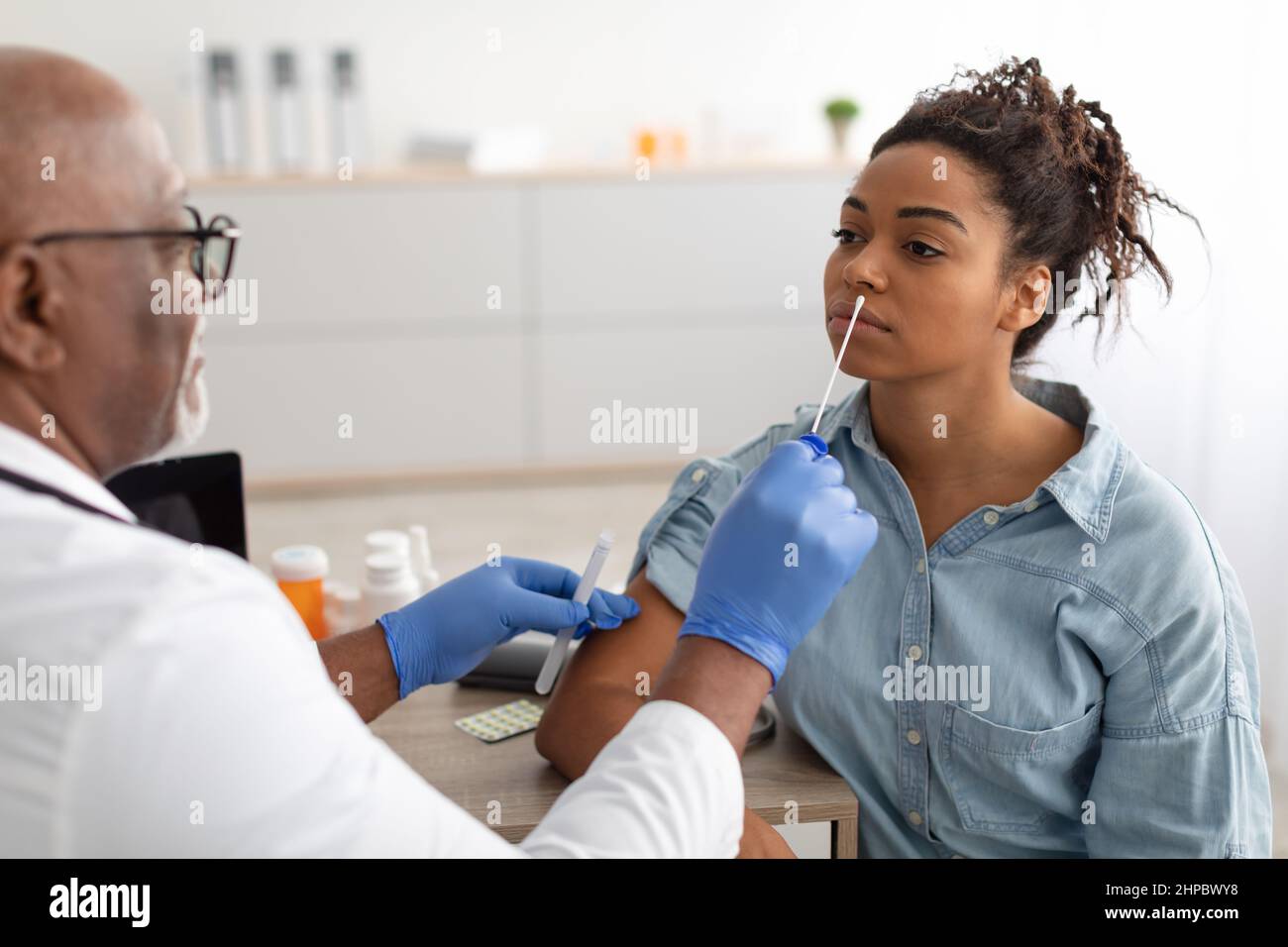Doctor taking PCR test sample from potentially infected black woman ...