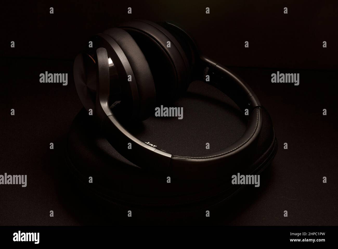 Modern wireless headphones with travel bag resting on black background ...