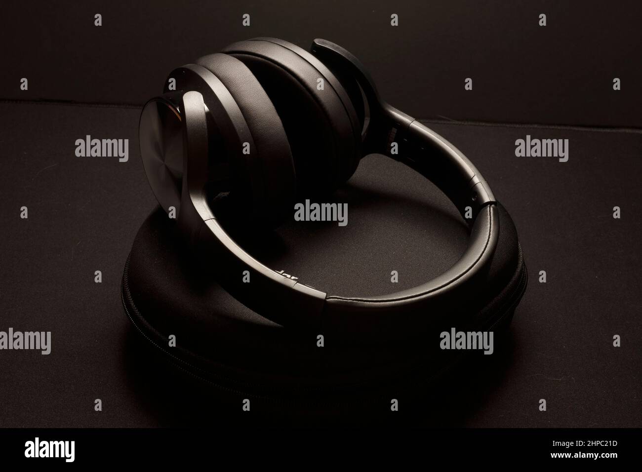 Modern wireless headphones with travel bag resting on black background ...