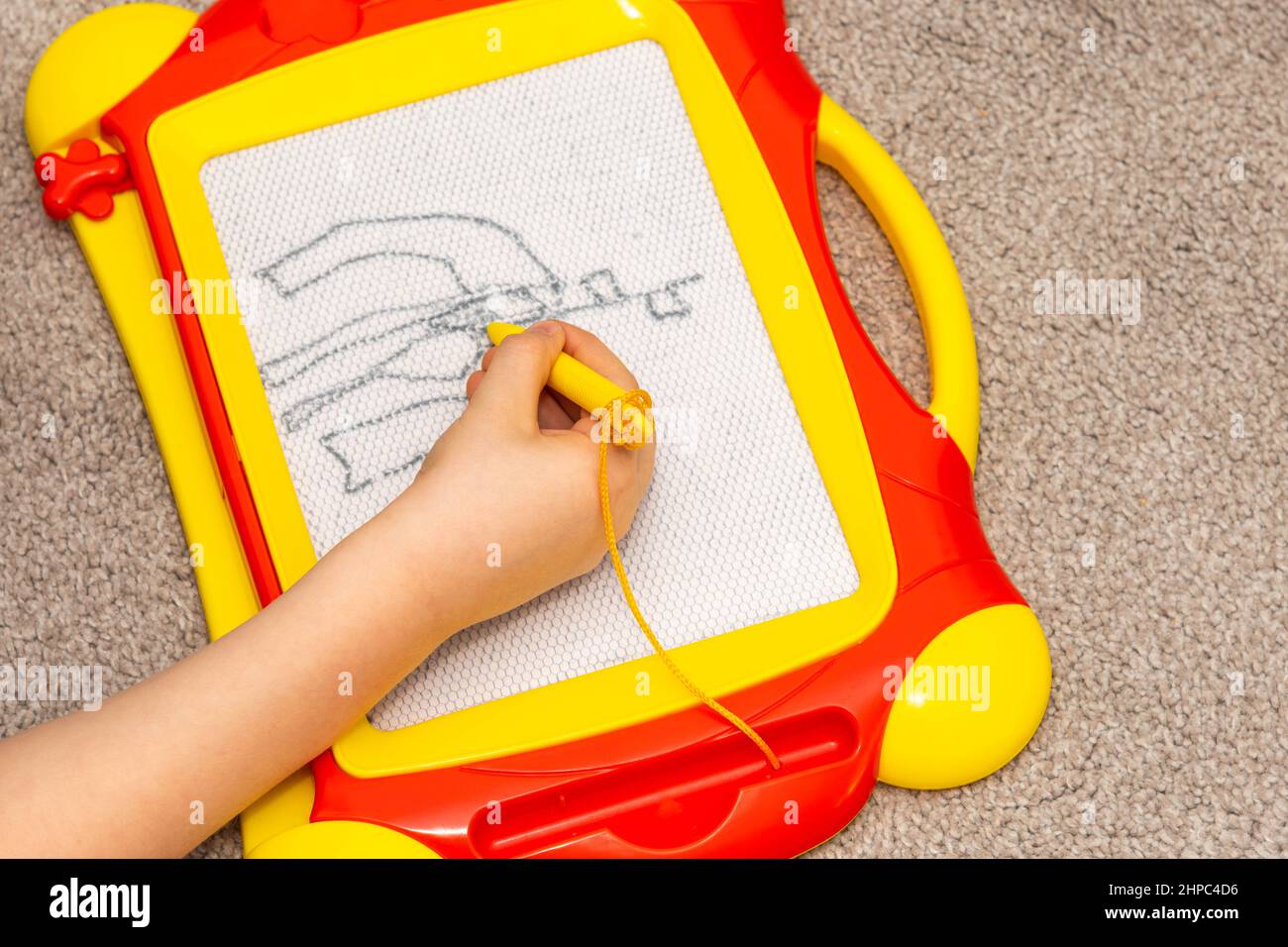 Child's hand drawing on educational drawing board that is magnetic and ...