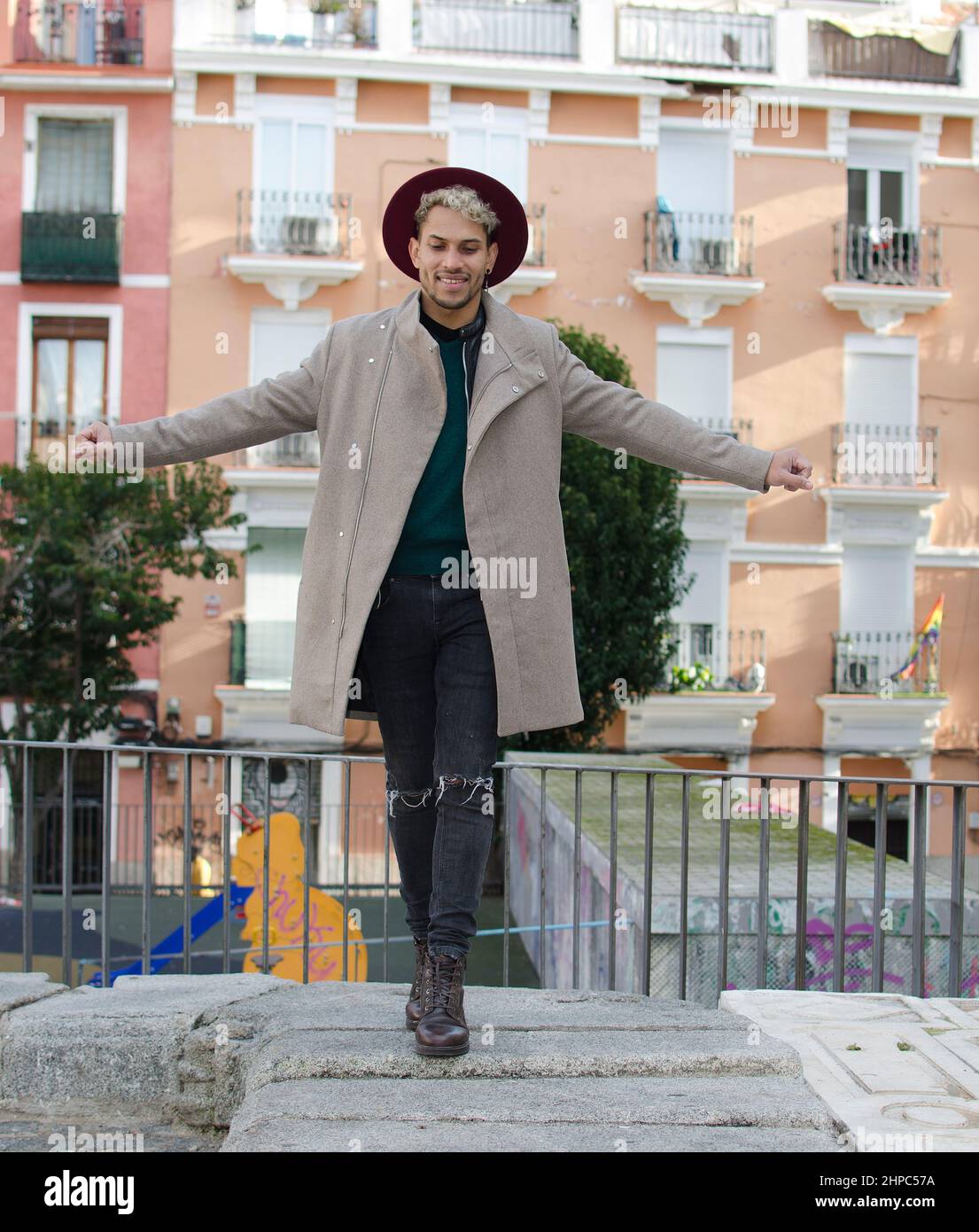 Fashion young model with grey jacket and red hat making funny balancing ...