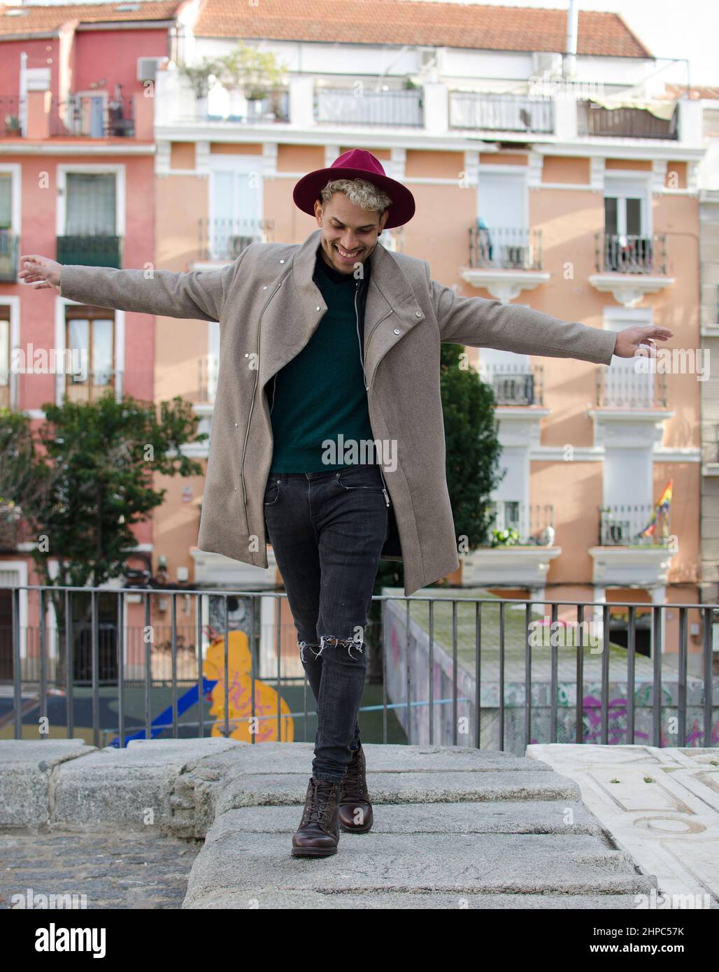 Fashion young model with grey jacket and red hat making funny balancing ...