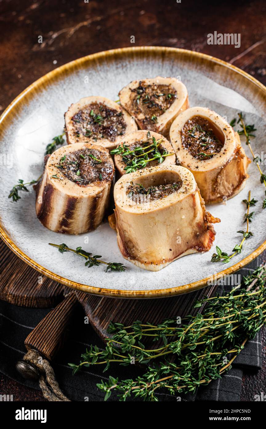 Baked marrow veal beef bones in plate with thyme and herbs. Dark ...