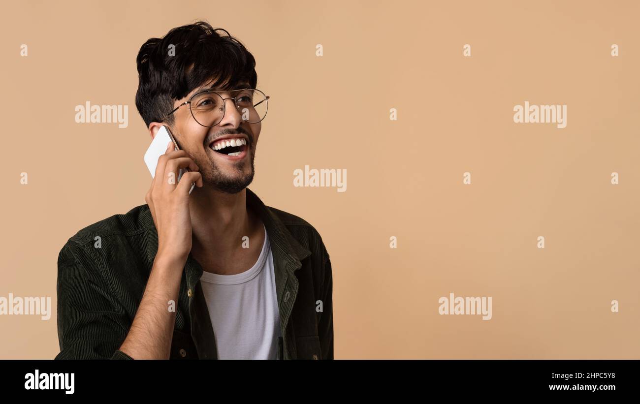Happy middle eastern guy having phone conversation on beige Stock Photo ...