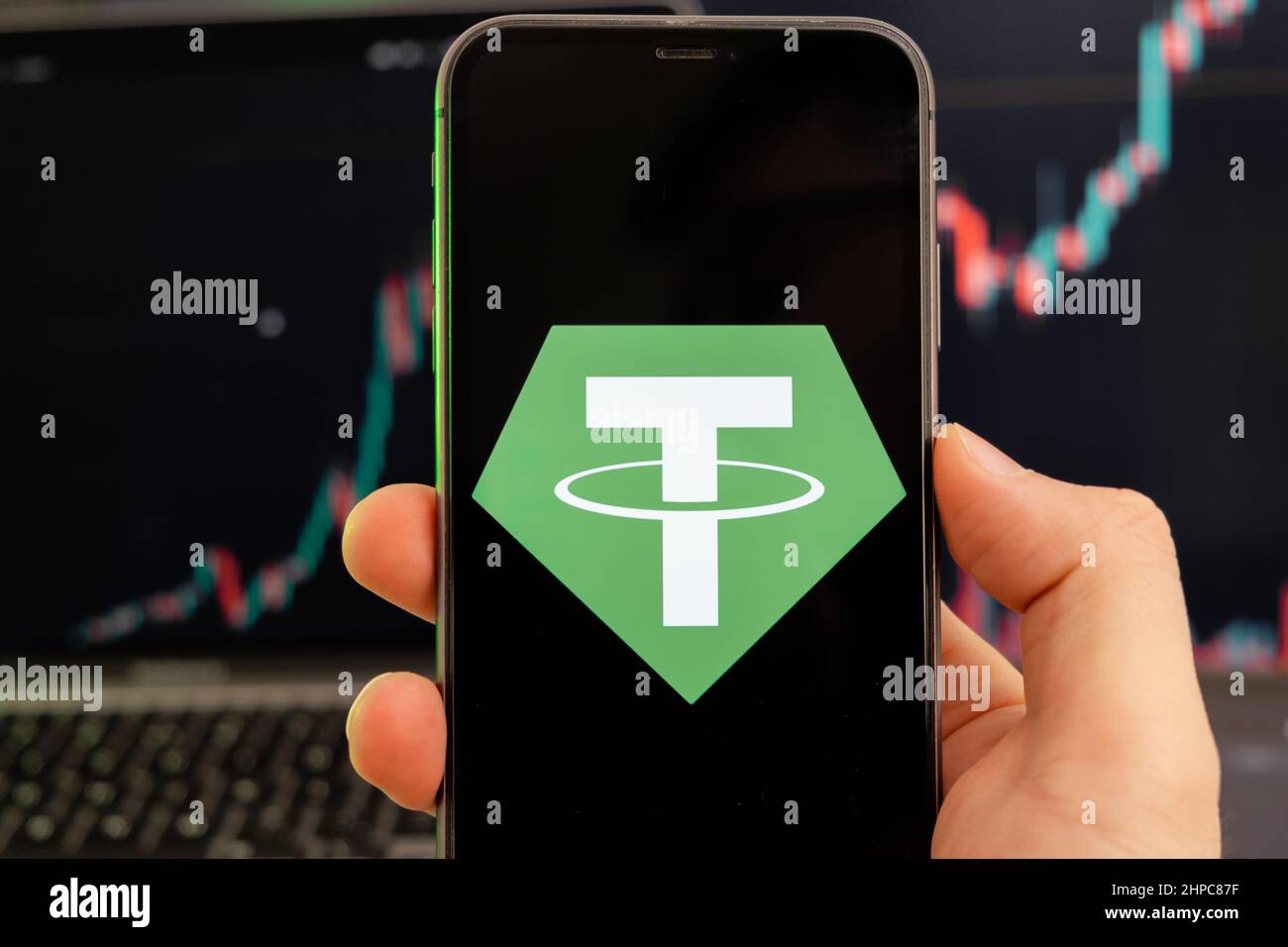 Tether USDT cryptocurrency logo on the screen of a smartphone in mans ...