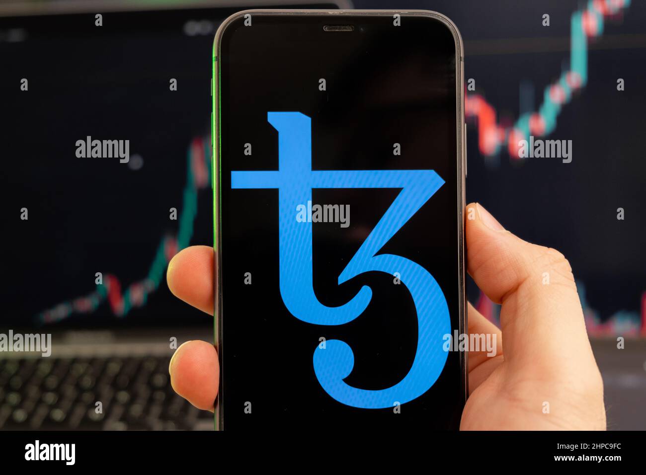 Tezos XTZ cryptocurrency logo on the screen of a smartphone in mans ...