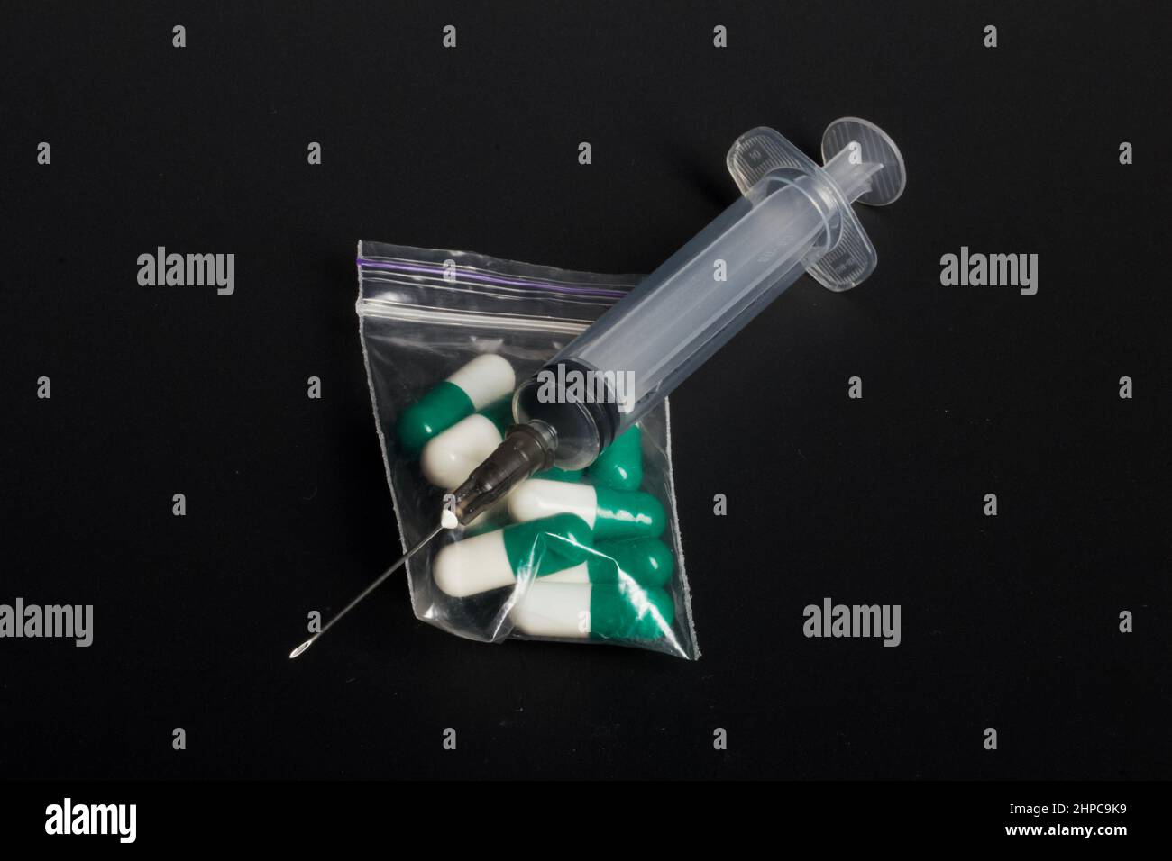 Pills are white-green. Medical syringe. Symbol of drug addiction. On a ...