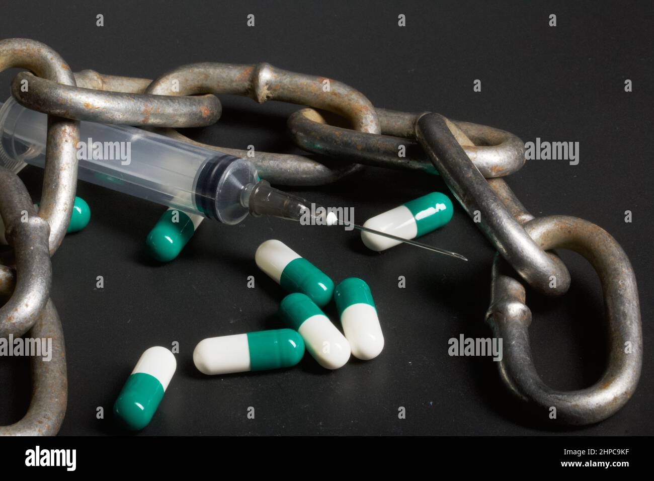 Pills are white-green. Medical syringe and metal chain. Symbol of drug ...