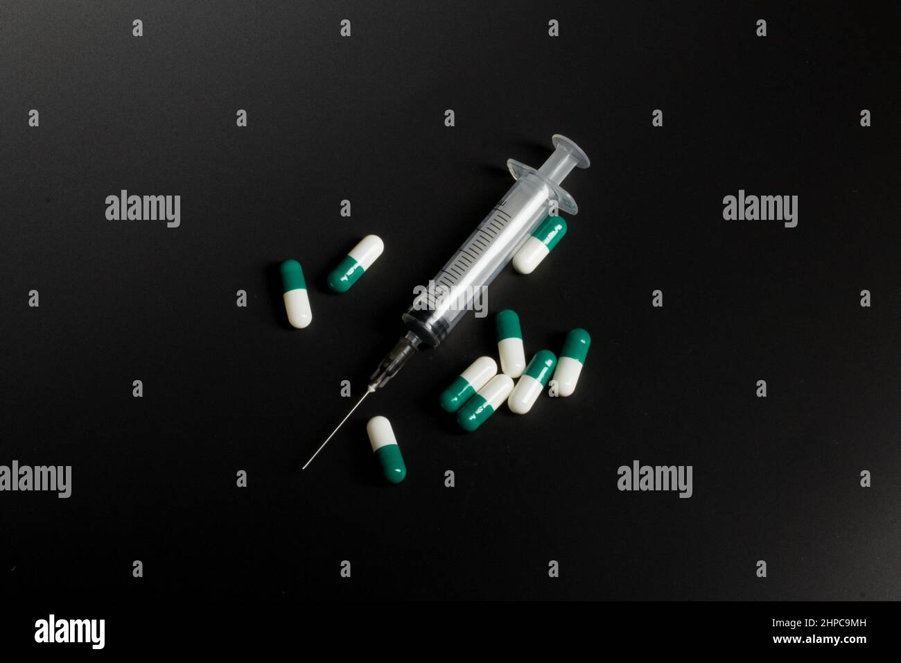Pills are white-green. Medical syringe and metal chain. Symbol of drug ...