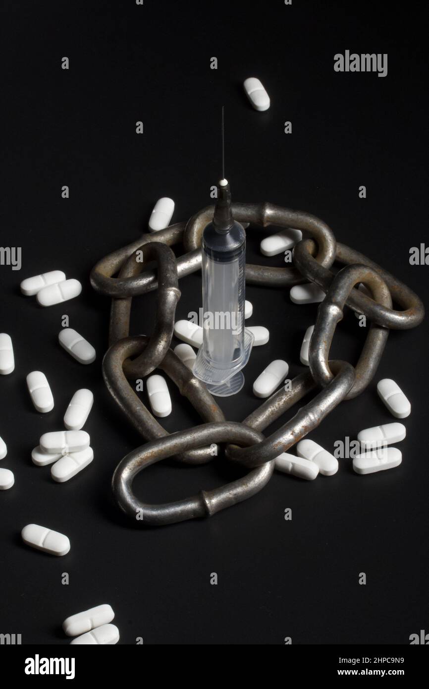 White tablets. Medical syringe and metal chain. Symbol of drug ...
