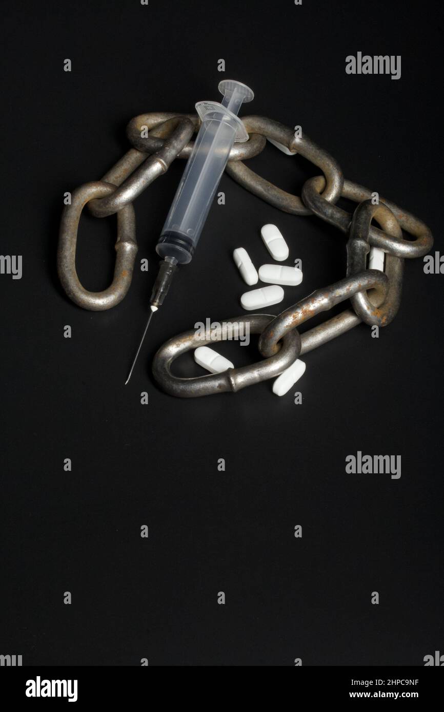 White tablets. Medical syringe and metal chain. Symbol of drug ...