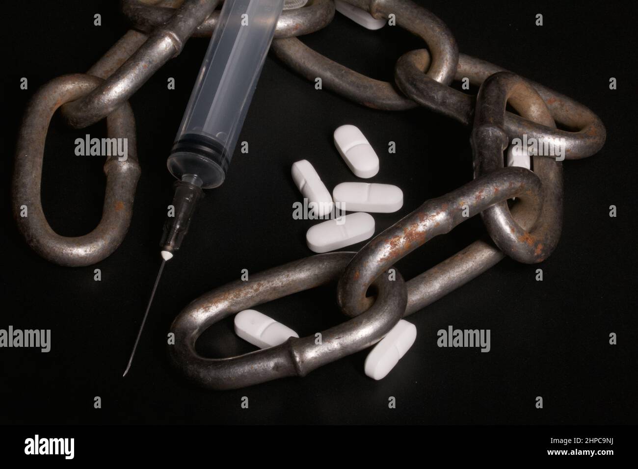 White tablets. Medical syringe and metal chain. Symbol of drug ...