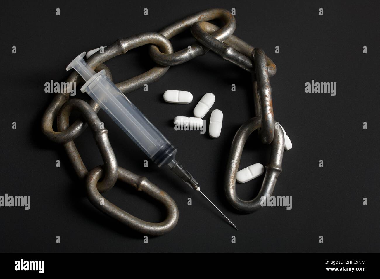 White tablets. Medical syringe and metal chain. Symbol of drug ...
