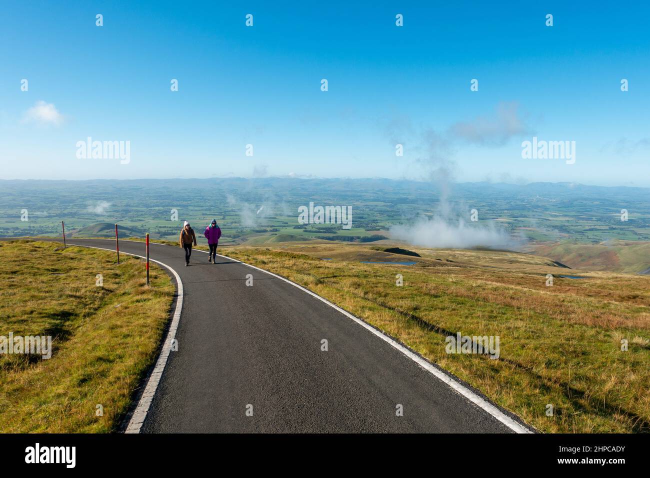 Walkers on the road to Great Dun Fell mountain in the Eden Valley on a ...