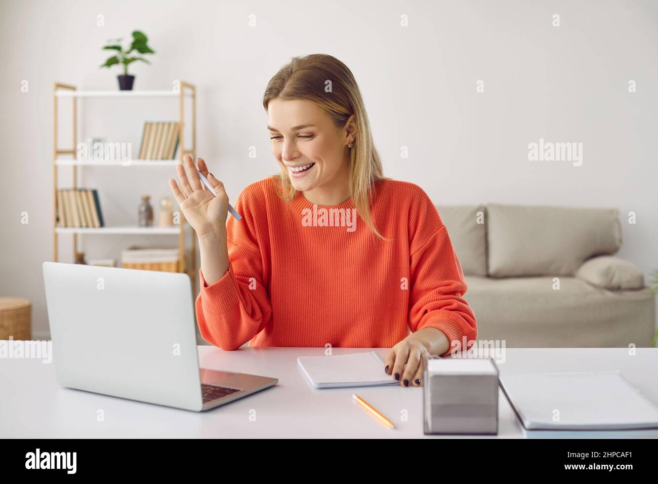 Happy student having online class on laptop, waving hello and writing ...
