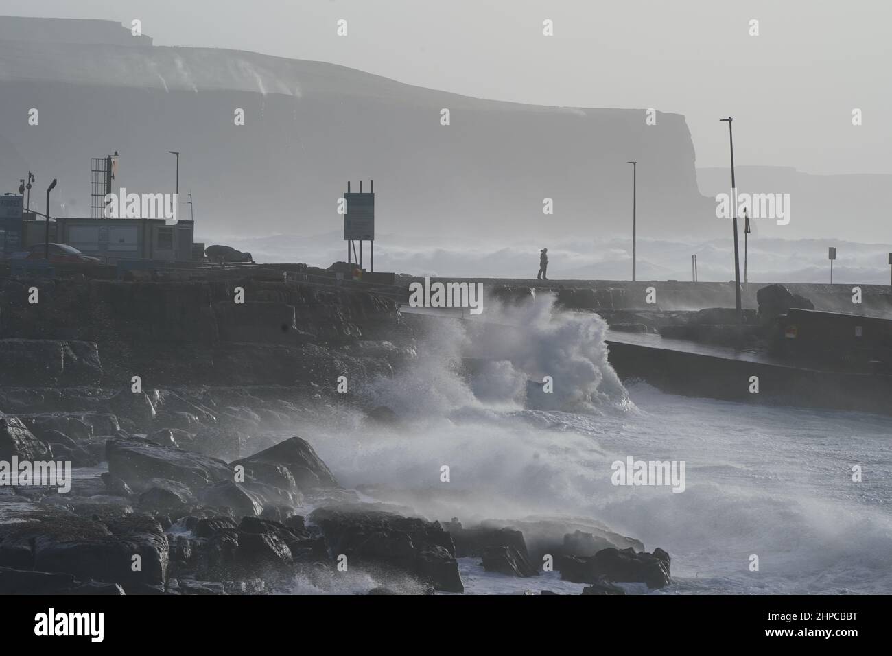 A person watches waves crashing against the shore at Doolin in County ...