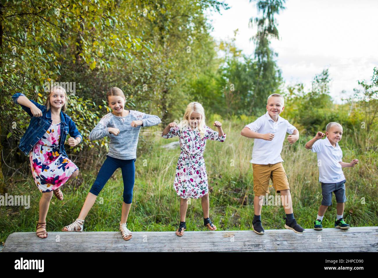 Five cute kids dancing outdoors on log Stock Photo - Alamy