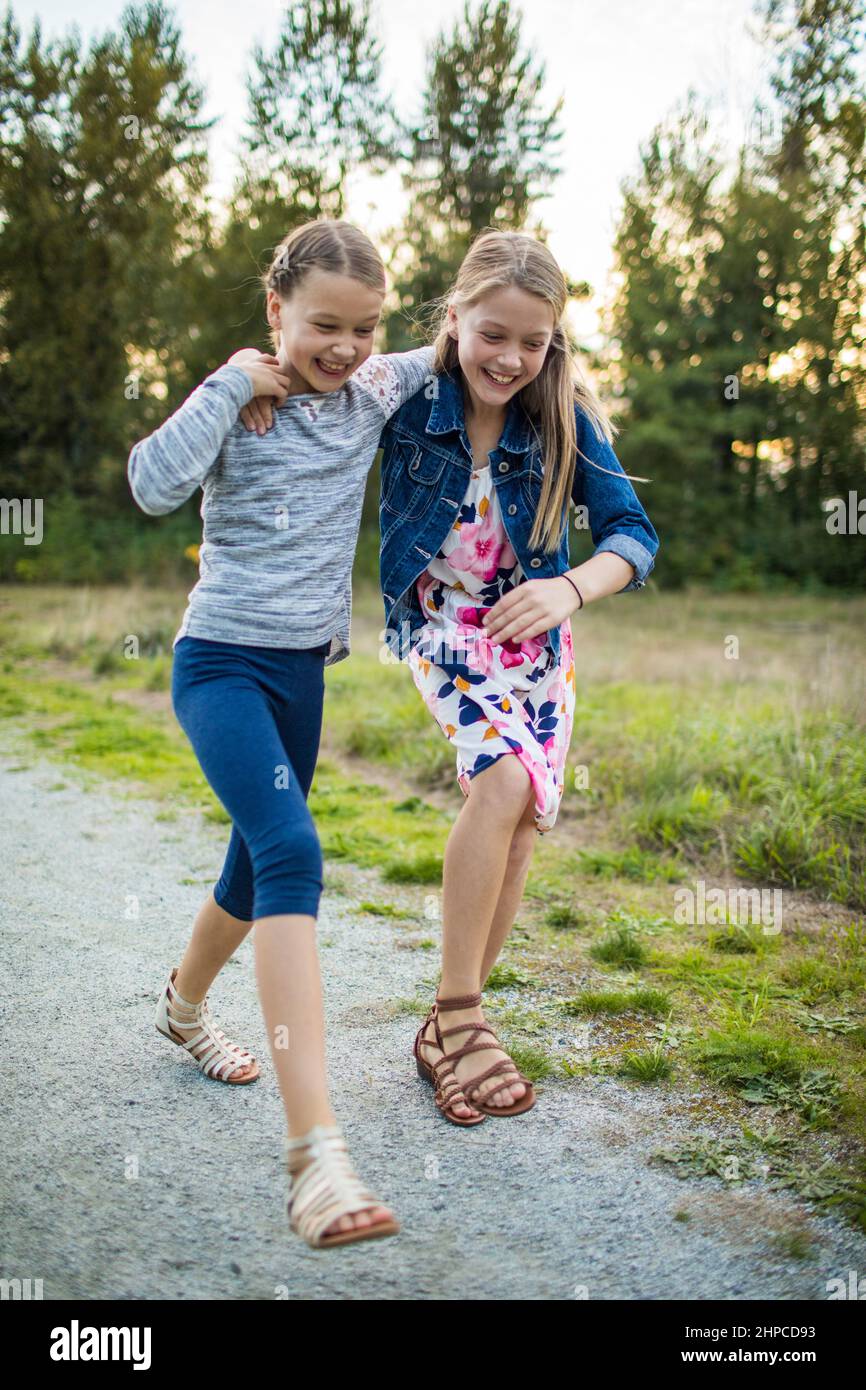 Two girls playfully laugh, touch on the move outside at the park Stock ...