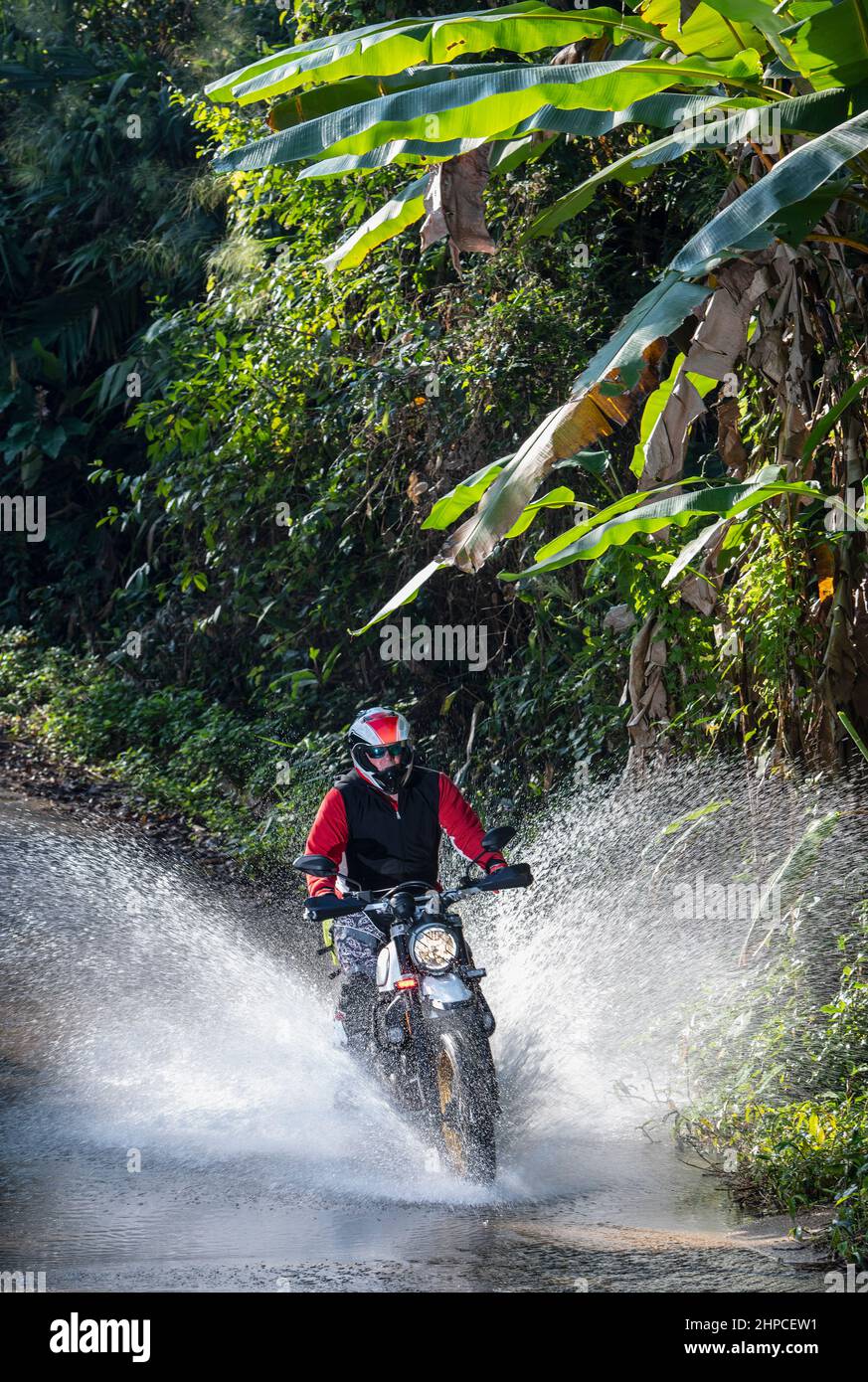 Man riding his scrambler type motorcycle through river in Thailand ...
