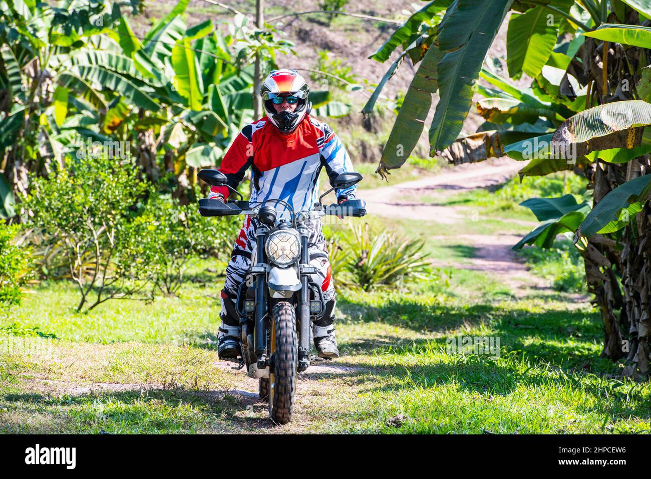Man riding his scrambler type motorcycle on rugged terrain in Thailand ...